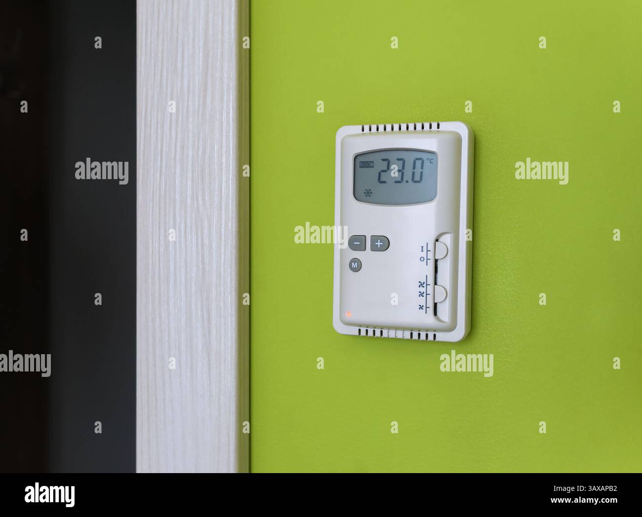 A wall-mounted climate control panel with a thermometer reading 23 ...