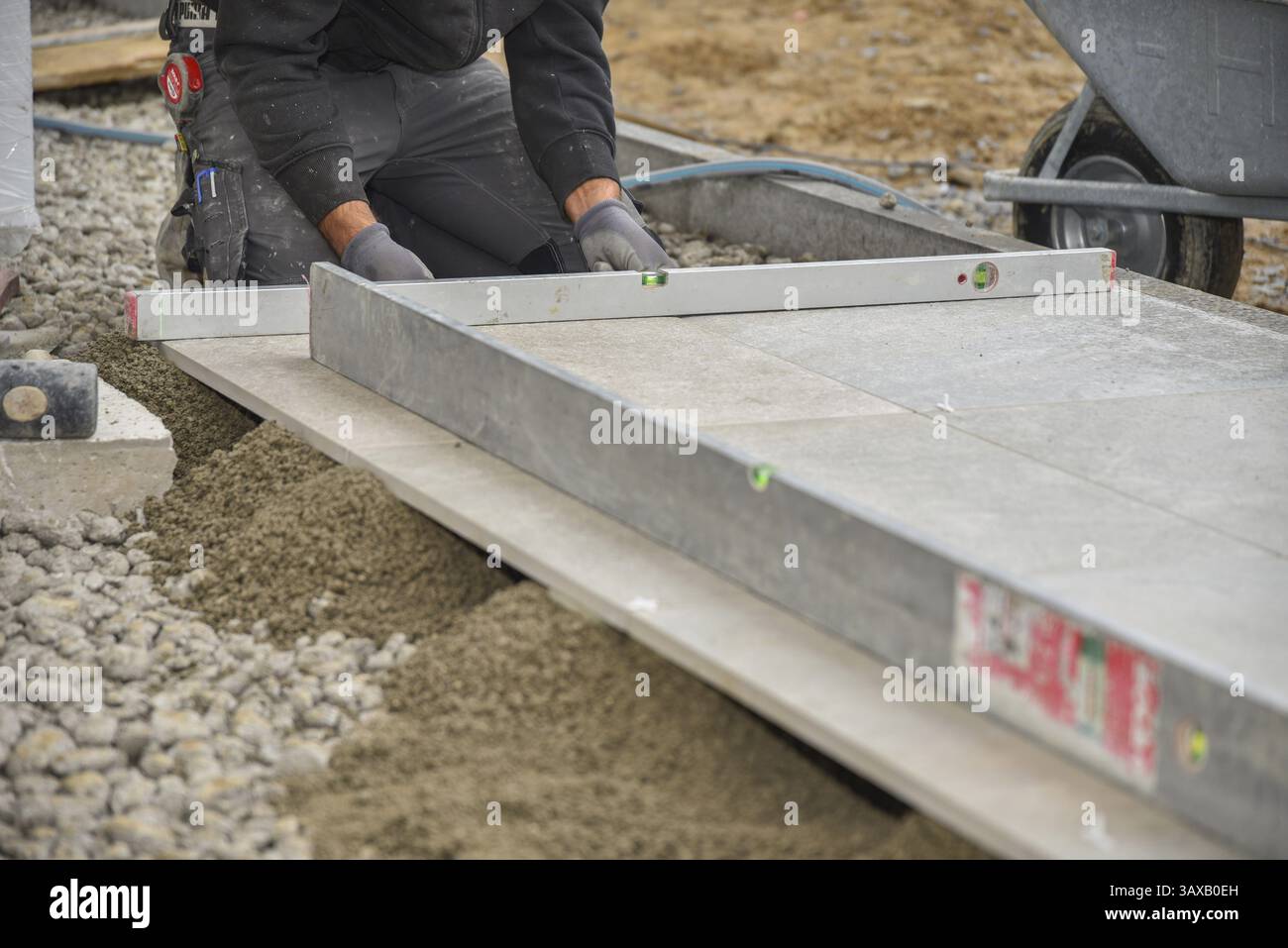Tiler laying tiles on a building site with spirit level Stock Photo - Alamy