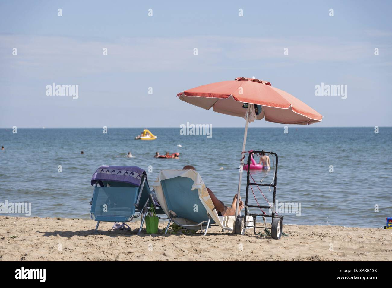 Holiday on the sandy beach on a deckchair and with a parasol in front ...