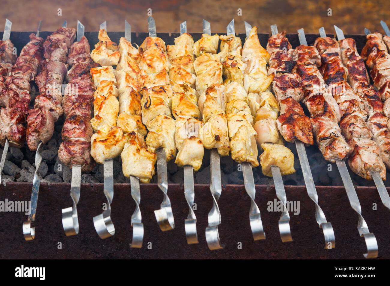Three types of meat on skewers on the grill. Pieces of pork, chicken ...