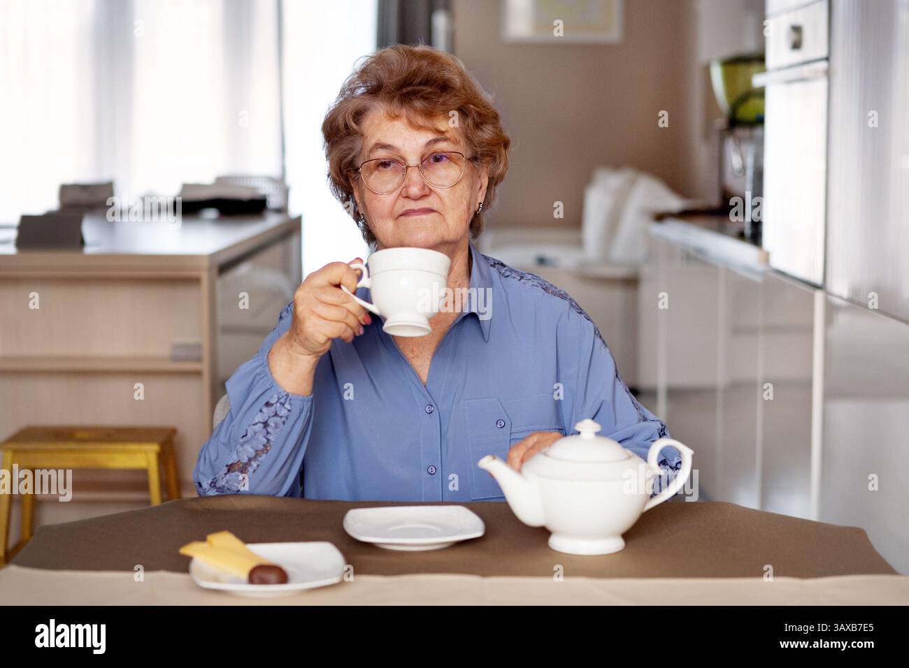 Older Woman in Blue Clothing Sitting Alone at Home, Drinking Tea and ...