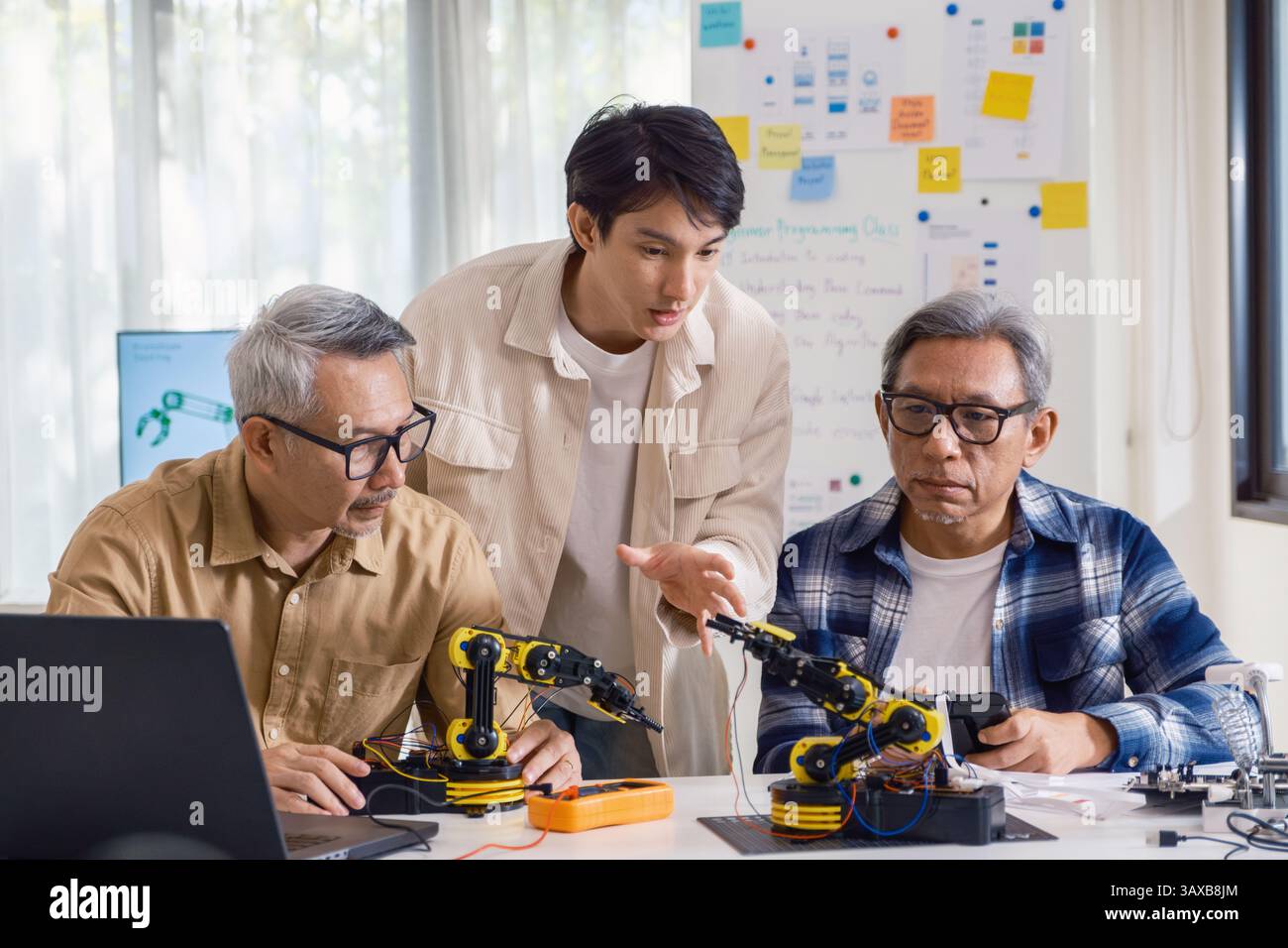 asian Robot arm engineers brainstorming in workshop to develop control technology with teamwork ...