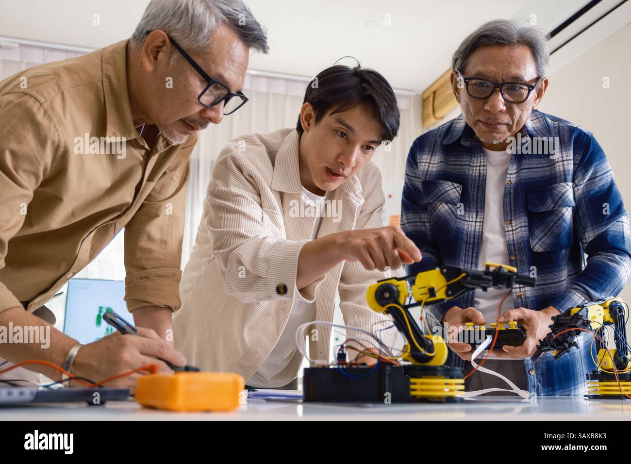 asian Robot arm engineers brainstorming in workshop to develop control technology with teamwork ...