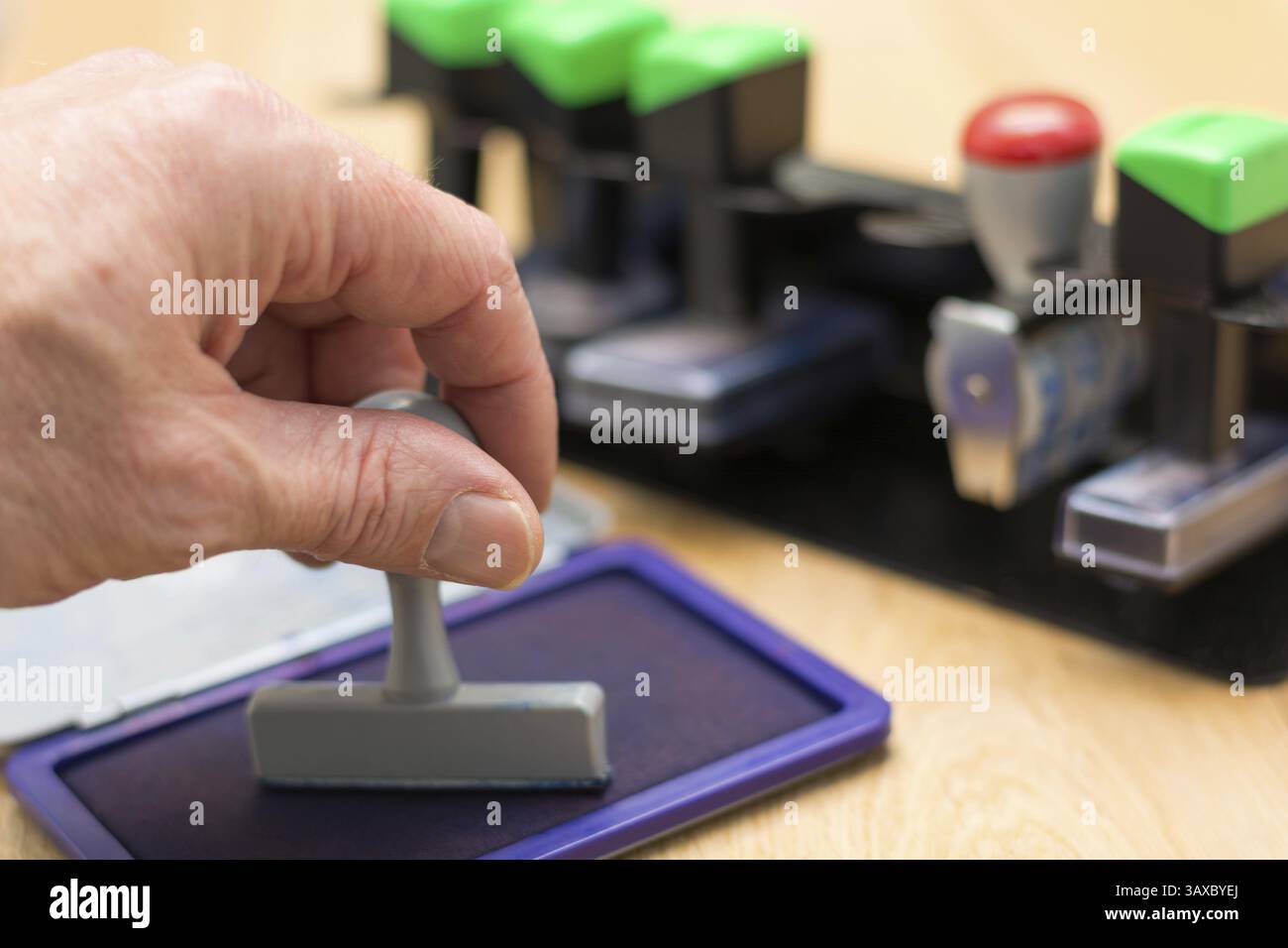 Hand presses long stamp into ink pad, behind it several stamps on stamp ...