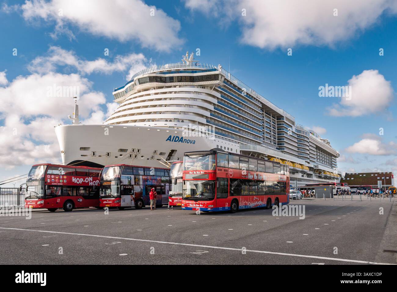 Four red hop-on hop-off buses parked at quayside in front of cruise ...