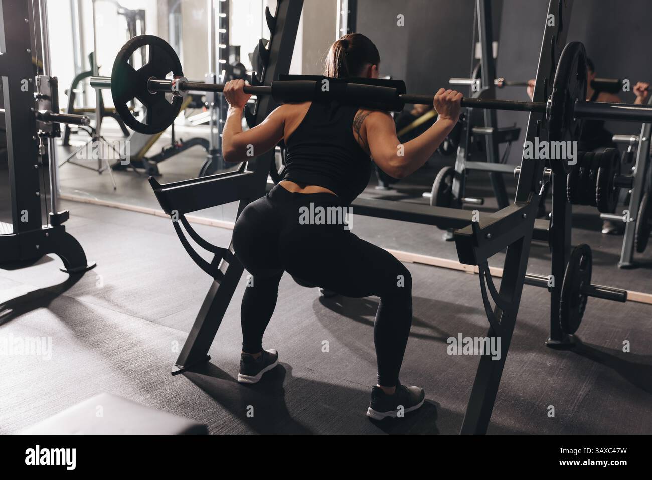 Athletic woman training with barbell in gym, back view Stock Photo - Alamy