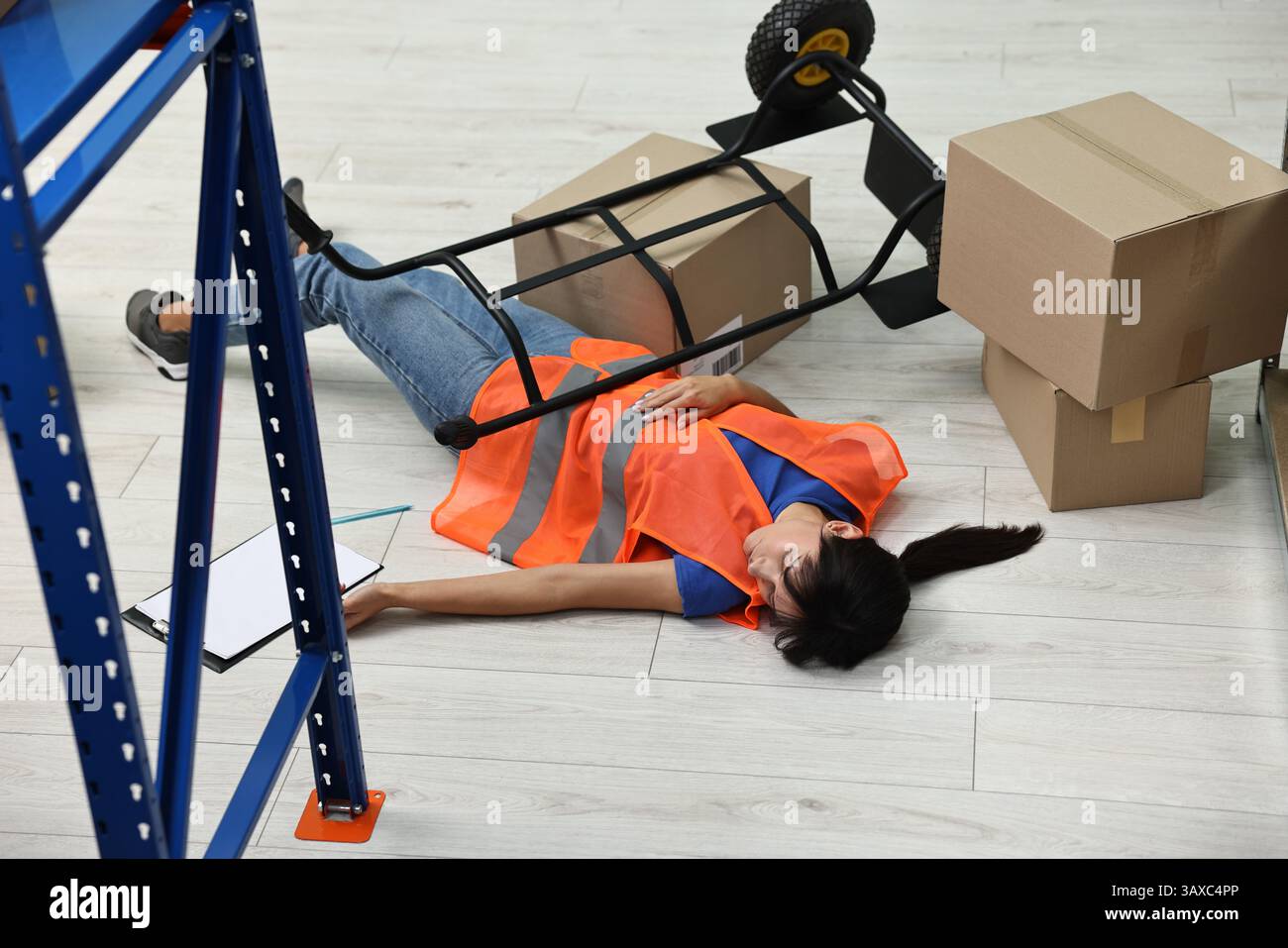 Accident at work. Unconscious woman and overturned hand truck on floor ...