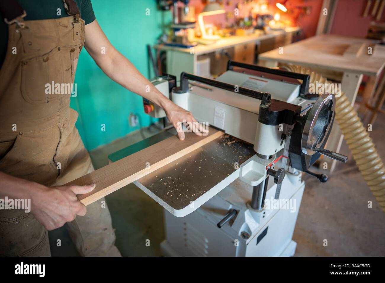 Skilled craftsman working with wood on planer thicknesser jointer ...