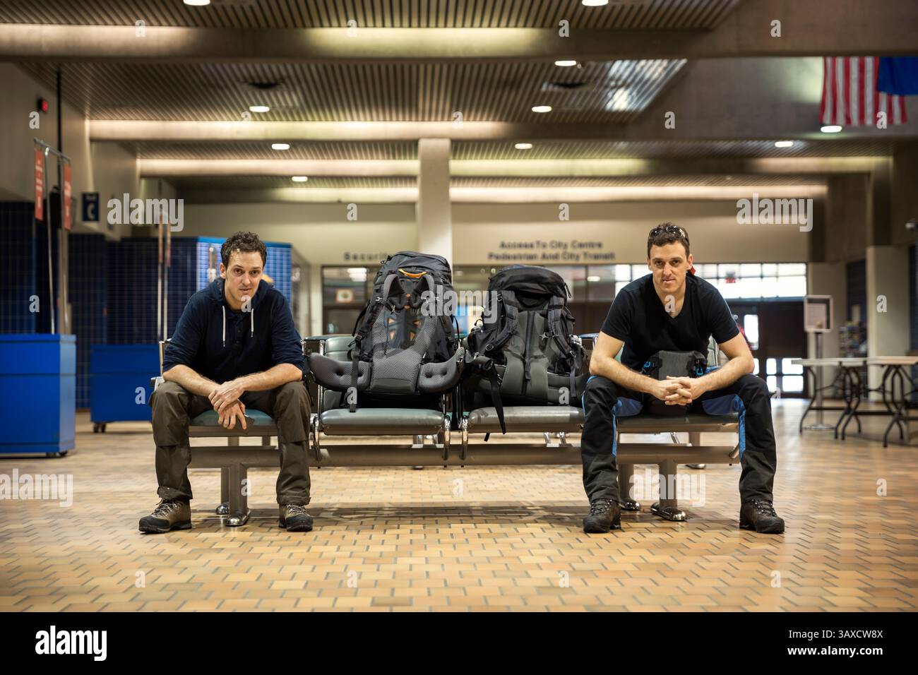 Backpackers sitting on bench inside bus station, Calgary, Alberta ...