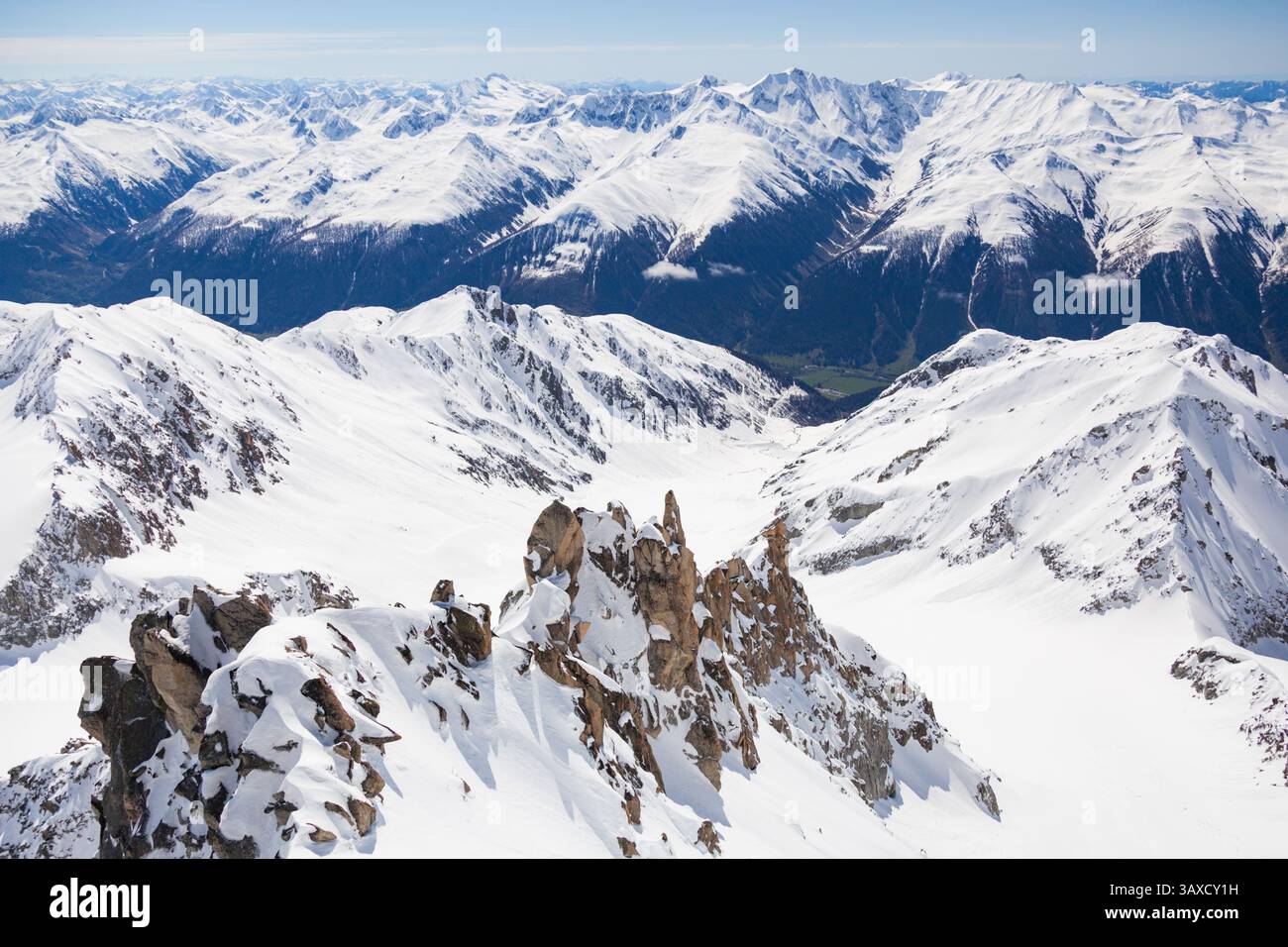 Snow-covered mountains to the horizon rising over deep green valley ...
