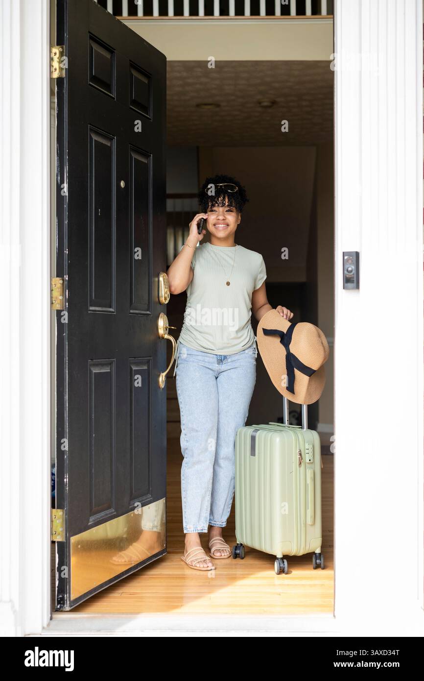Woman leaving house with luggage for summer Stock Photo - Alamy