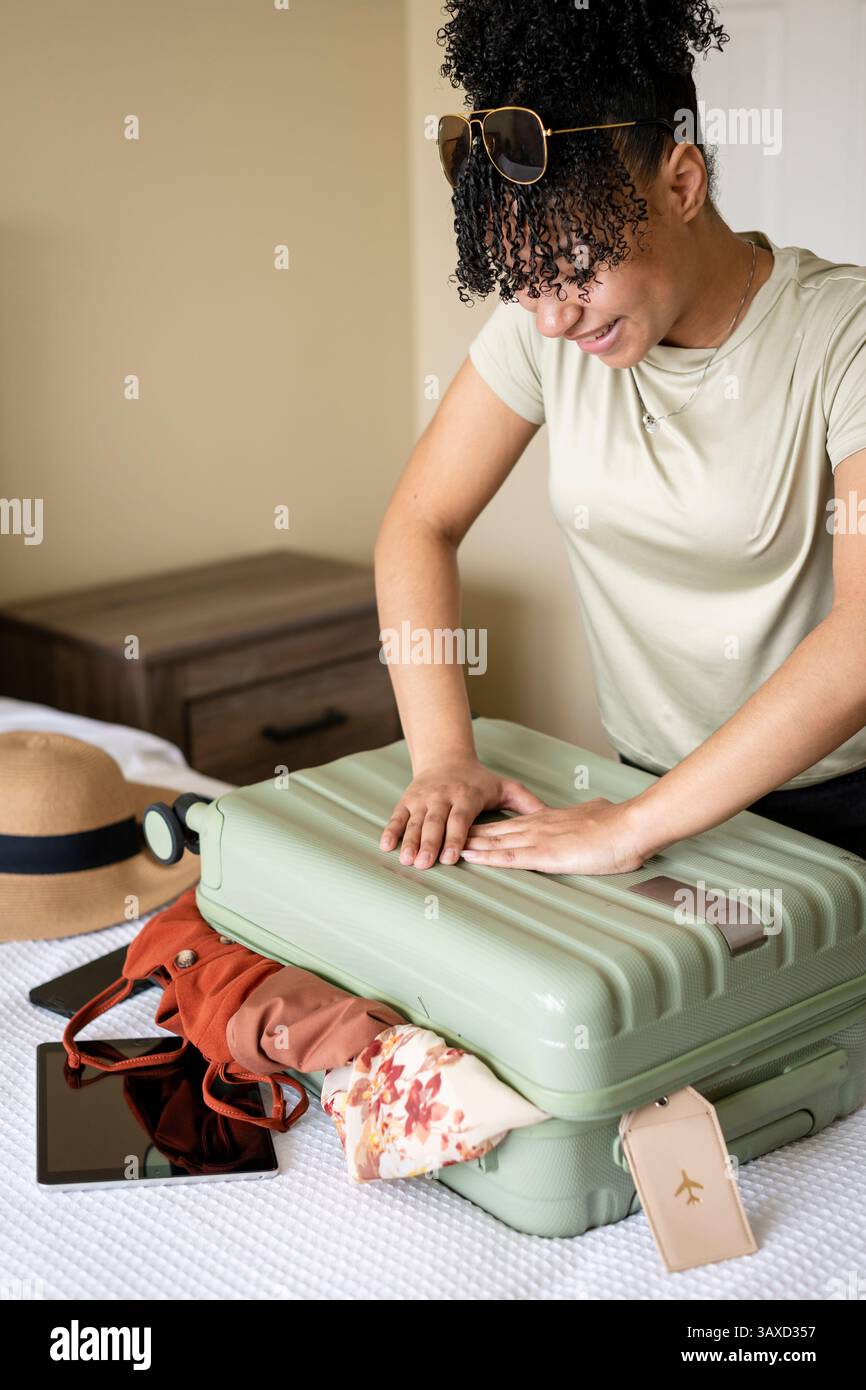 Woman laughs while trying to push suitcase down to close it Stock Photo ...