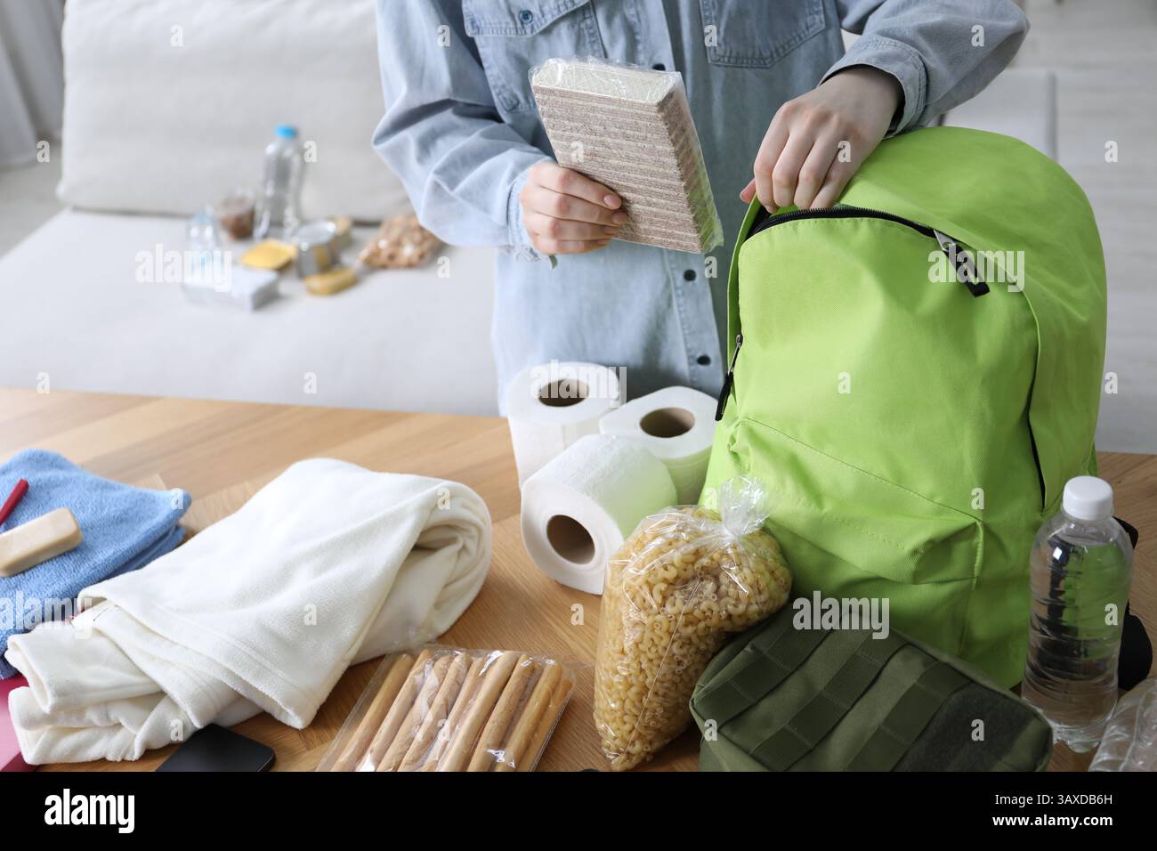 Survival kit. Woman packing different emergency supplies at wooden ...
