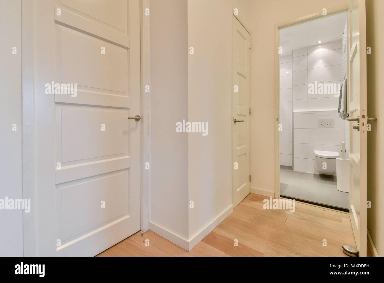 A sleek, modern hallway featuring white doors, leading to a ...
