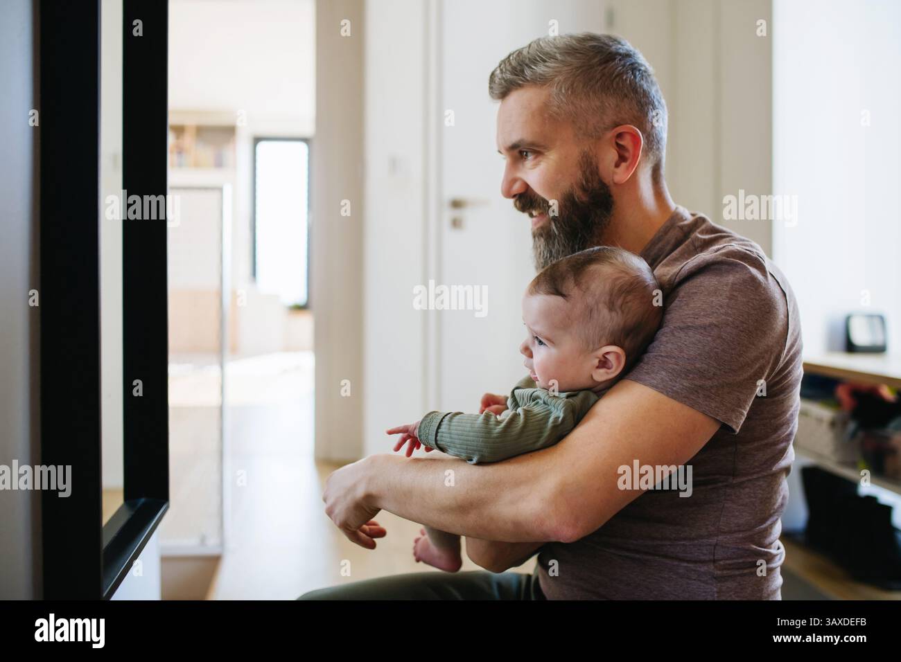 Portrait of father holding baby son in arms, looking in mirror Stock ...