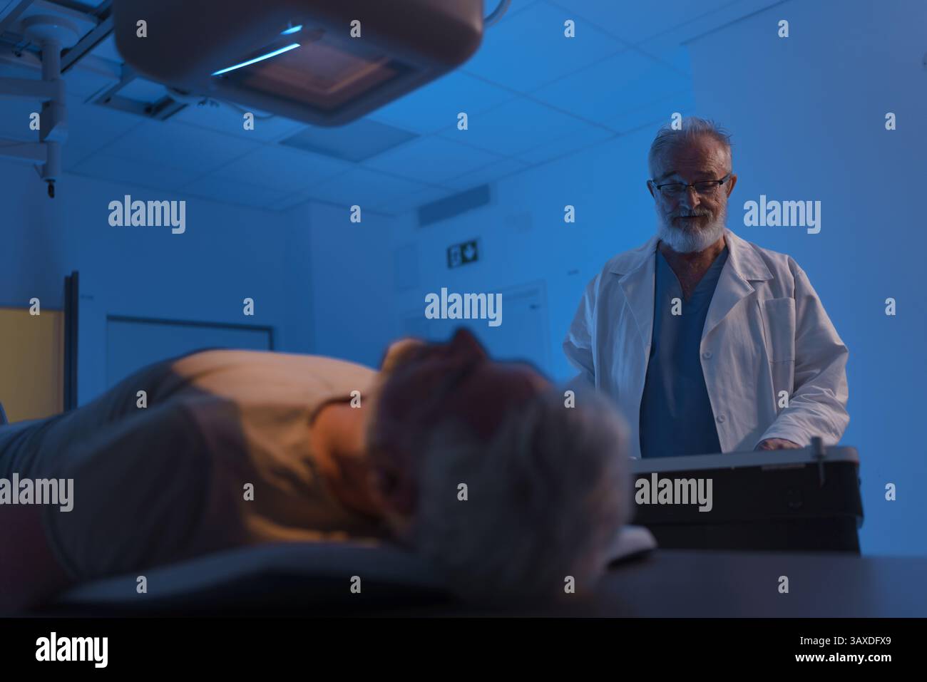 Radiologist performing X-ray examination on male patient using tilting ...