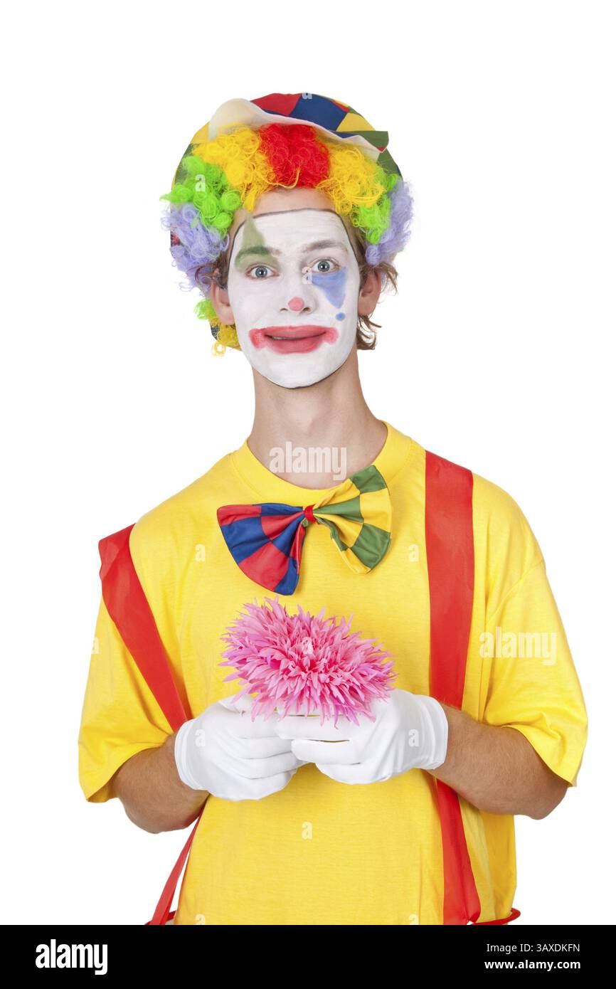 Young man as clown holding pink plastic flower - isolated Young man as ...