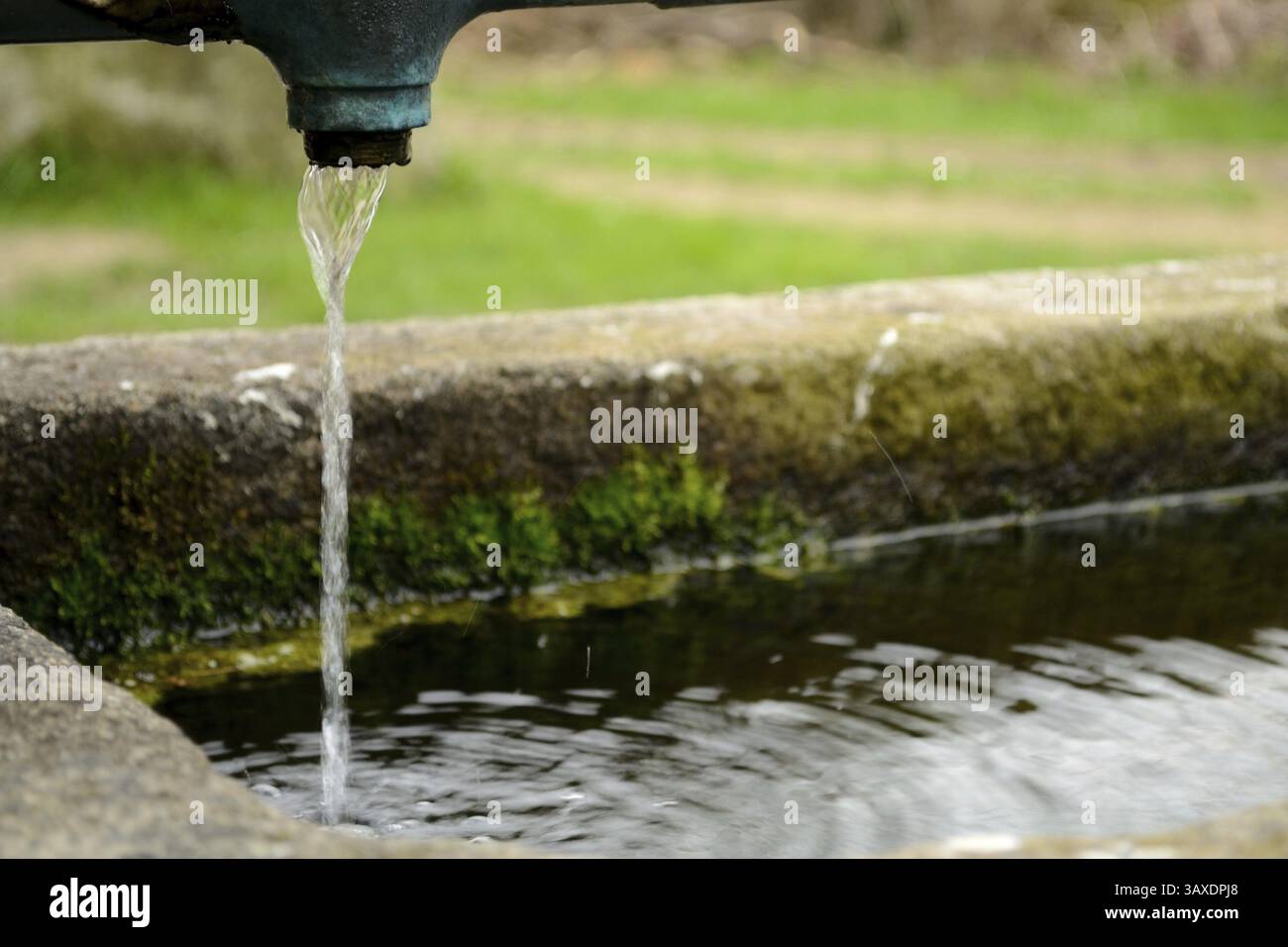 Old granite water trough with running water Stock Photo - Alamy