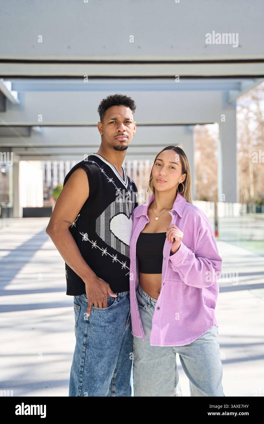 Fashionable young multi ethnic couple posing together under a modern ...