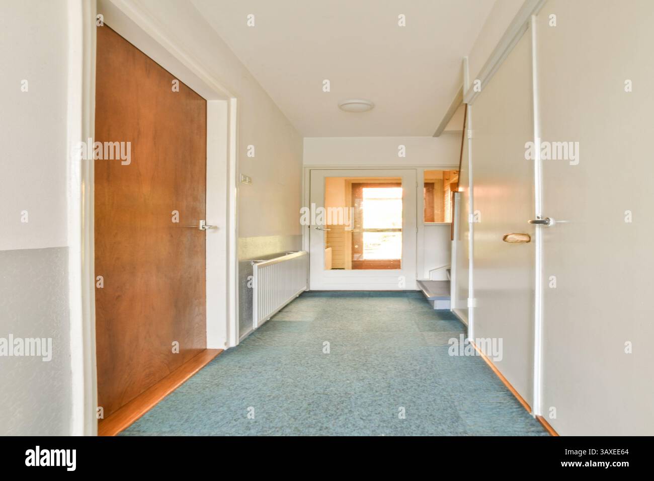 A bright and spacious hallway featuring wooden doors, light walls, and ...