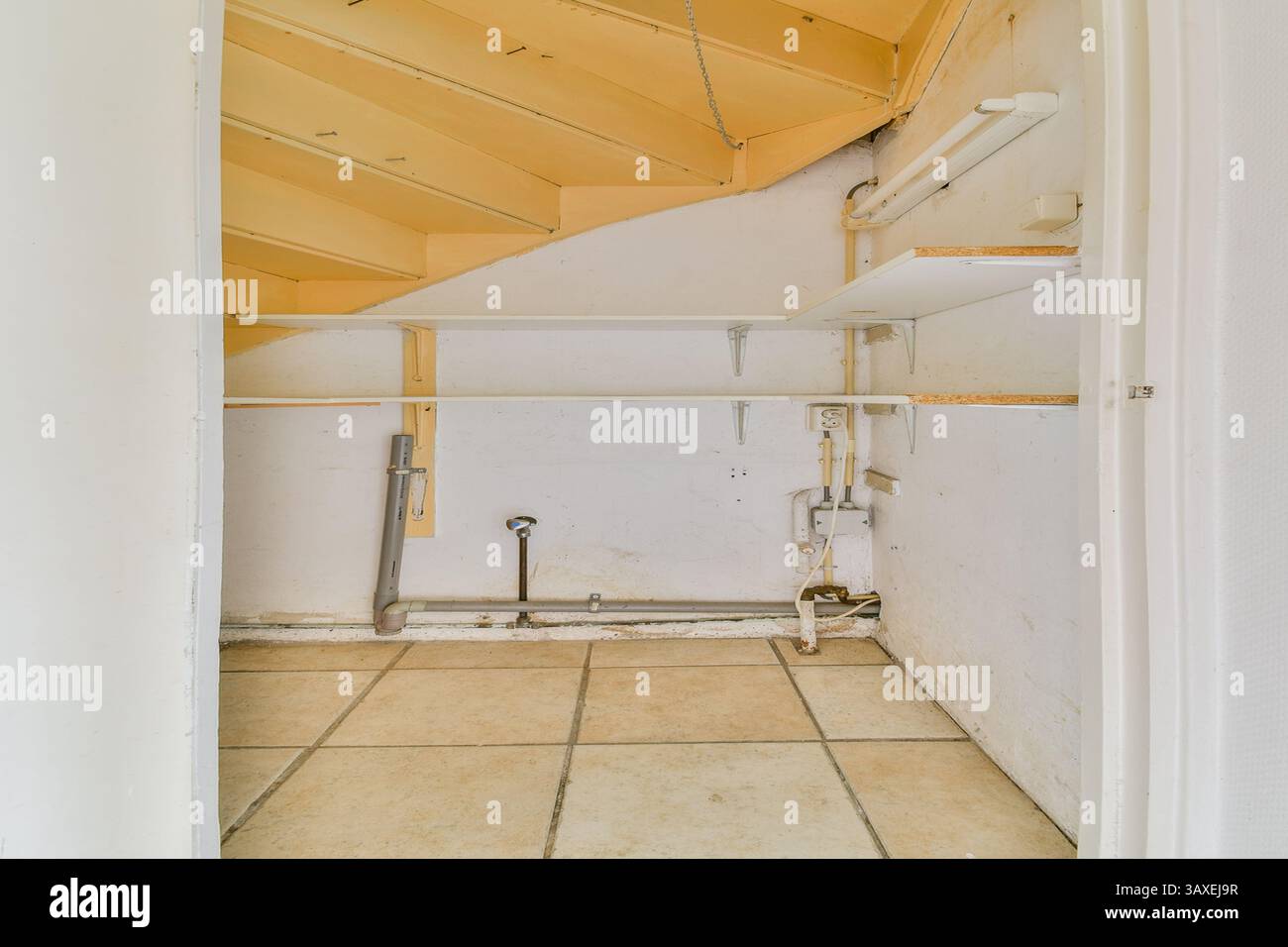 An empty, organized storage area located under a staircase. The space ...