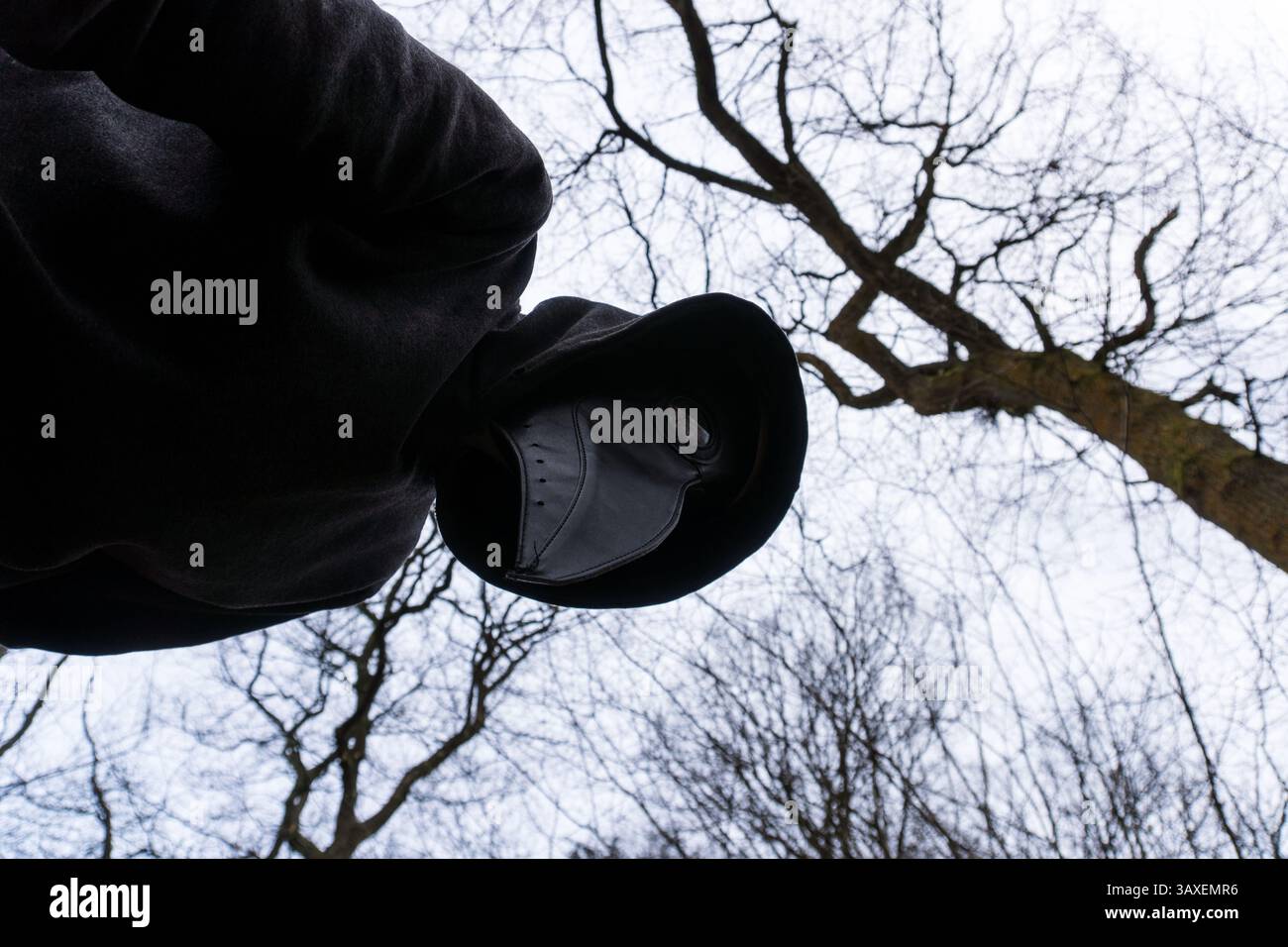 A low angle looking up at a horror figure wearing a plague doctor mask ...