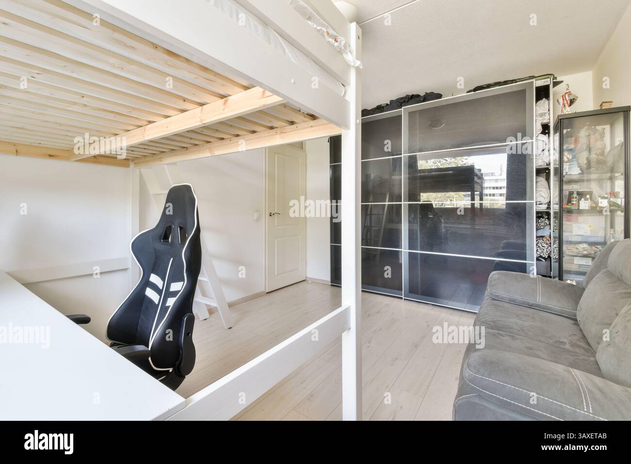 A well-lit, modern minimalist bedroom featuring a loft bed and a small ...