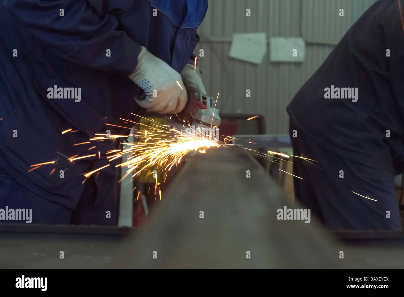 A worker works with an angle grinder. Sparks fly from the grinder Stock ...