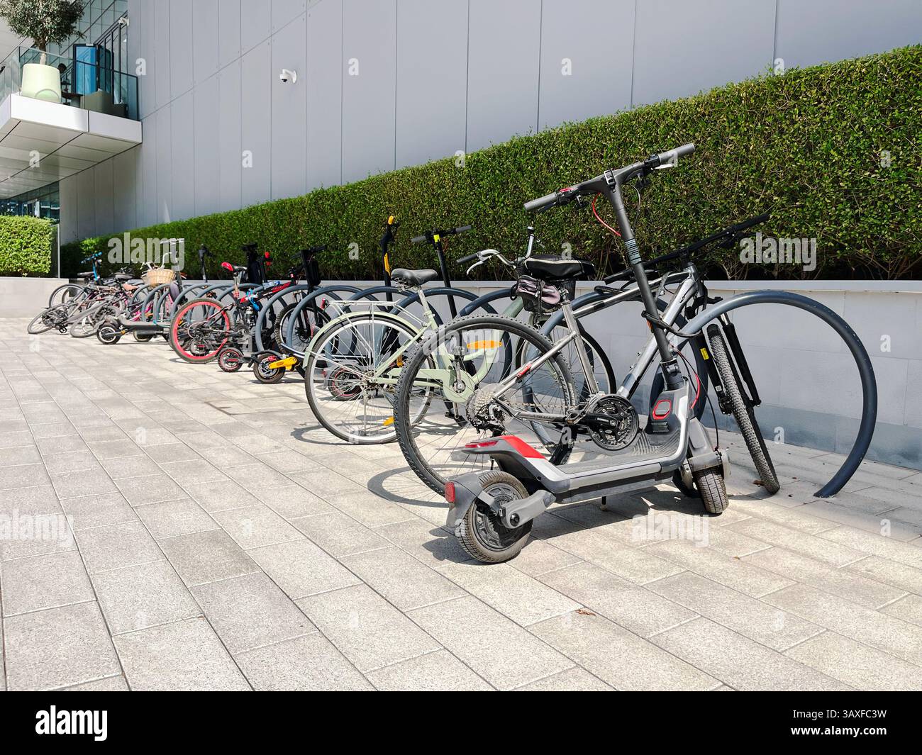 A row of parked bicycles and electric scooters in a designated parking area. Sustainable ...