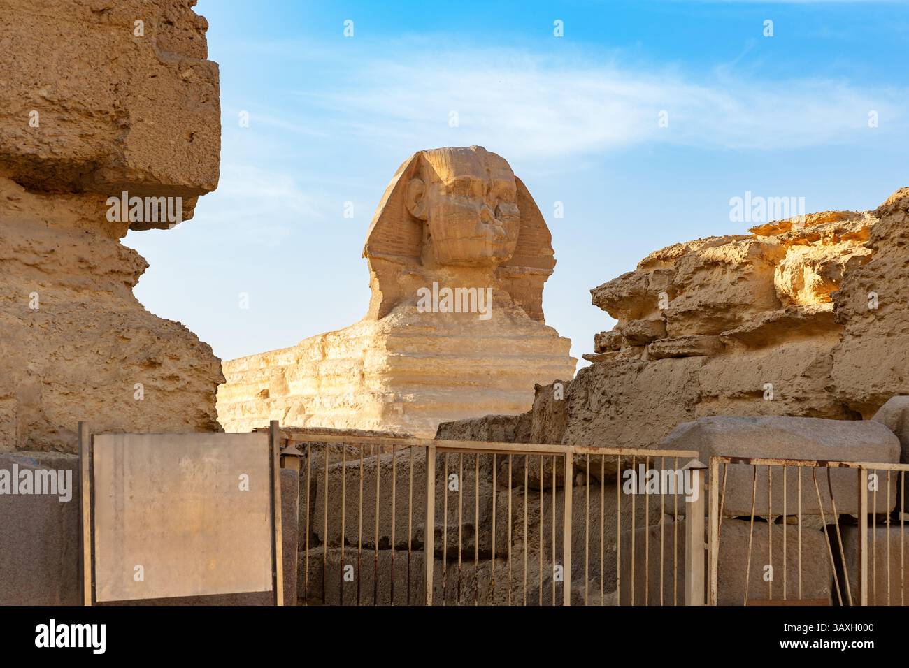 Sphinx stands majestically among ancient ruins at Giza beneath a bright blue sky in the ...