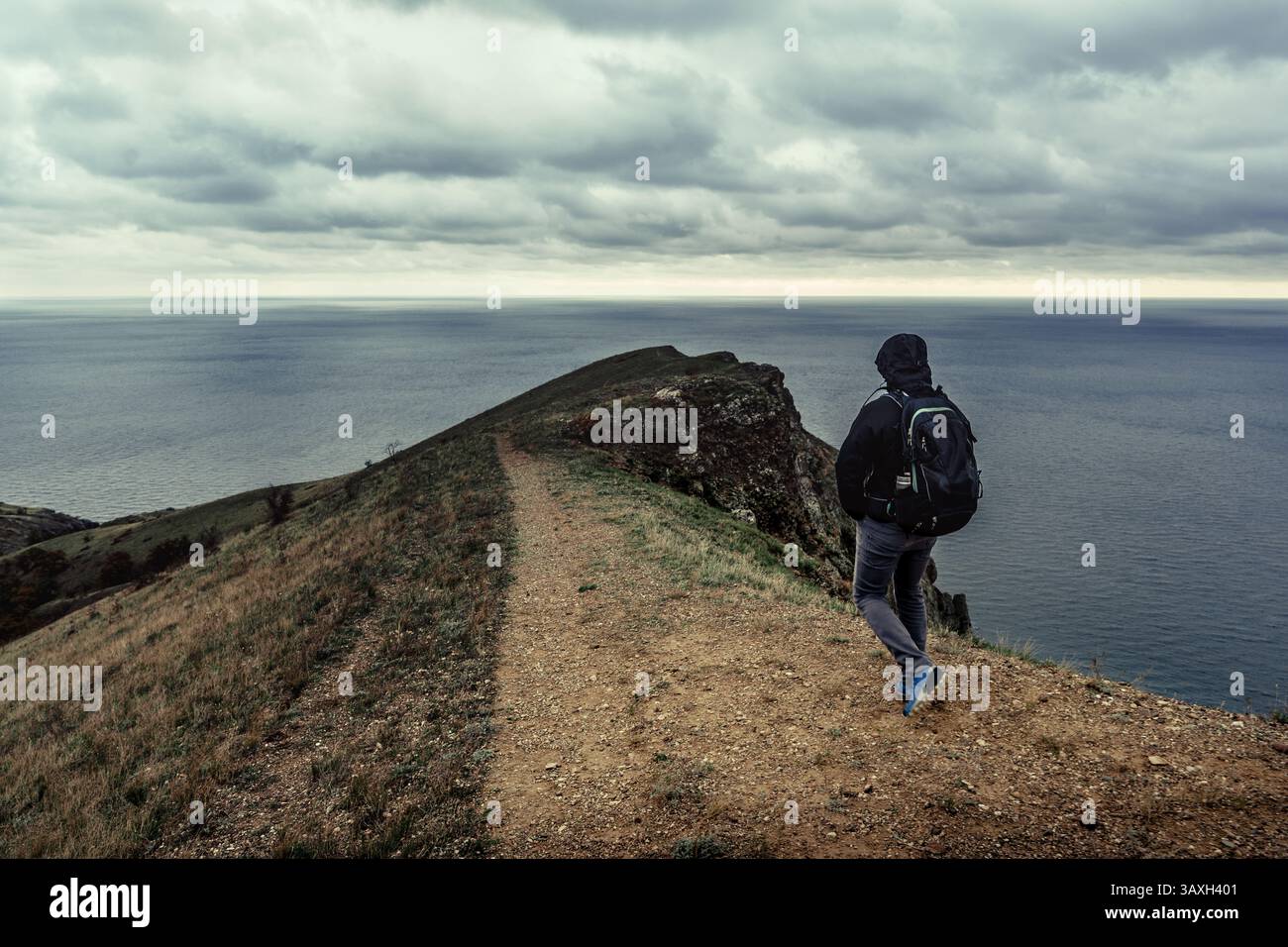 Exploring a coastal trail overlooking the ocean under a moody sky ...