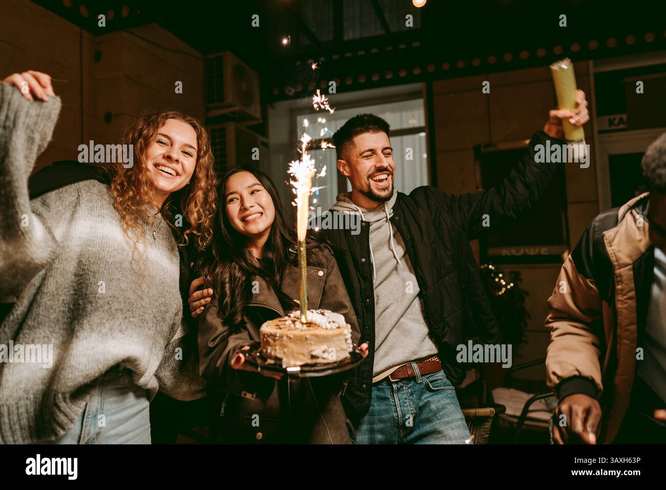 Celebration with friends indoors featuring a birthday cake and ...