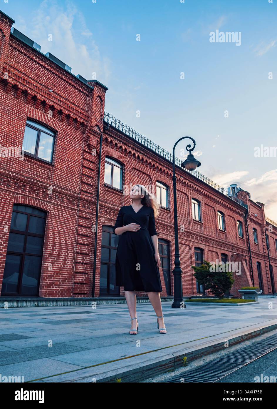Elegant pregnant woman poses outdoors in a stylish black dress near ...
