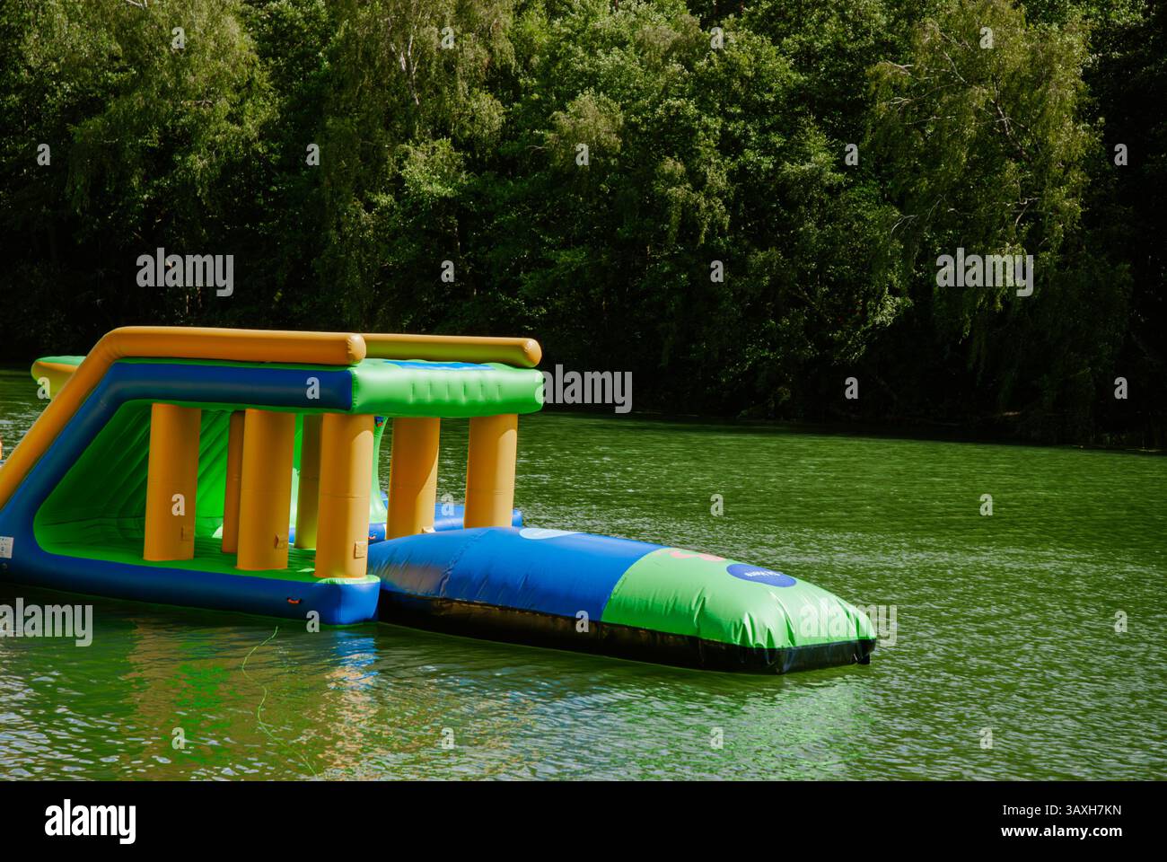 Inflatable water park obstacle course on a lake amidst lush greenery ...