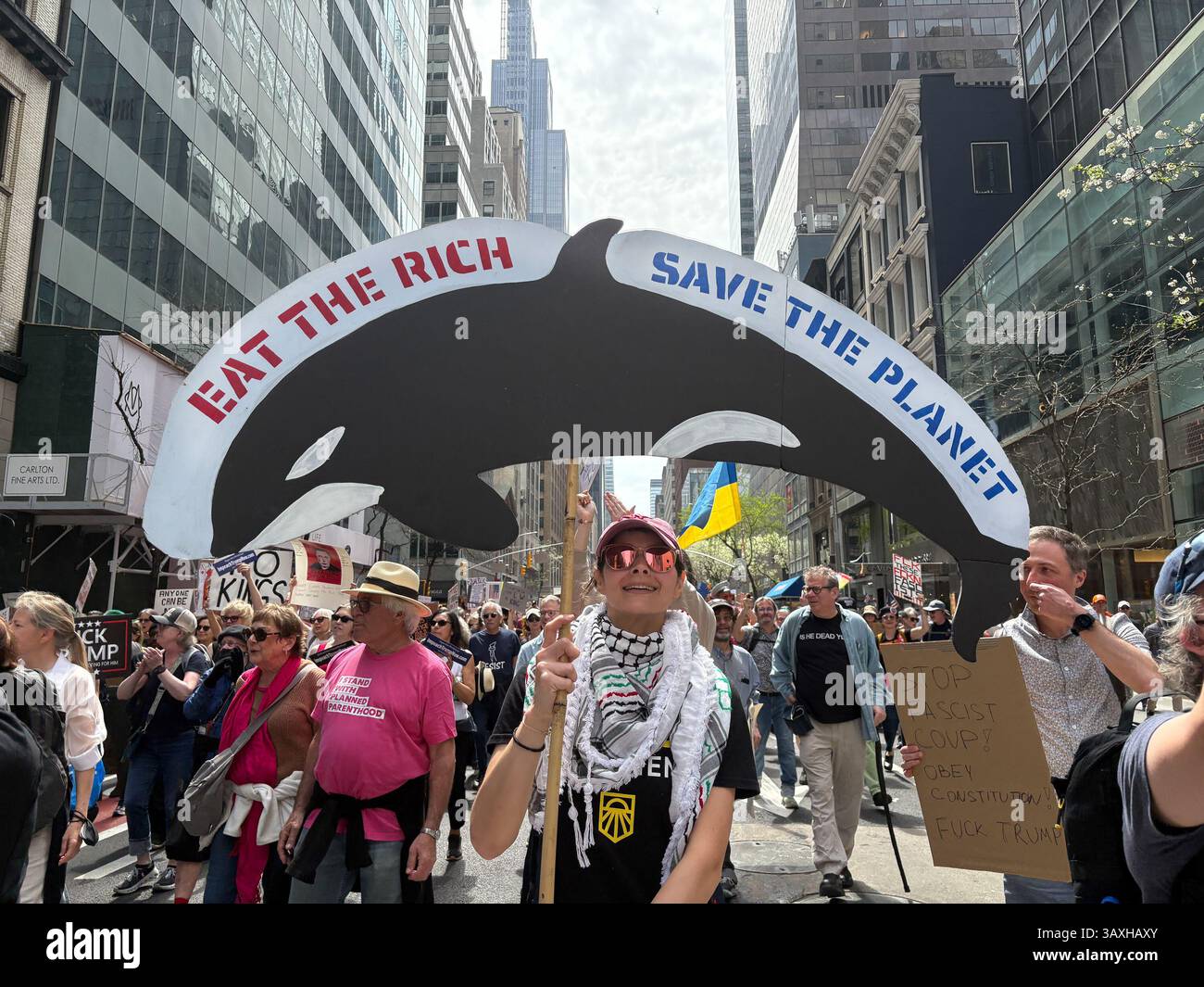 Protesters walk under 'Eat the Rich and Save the Planet ' signs during ...