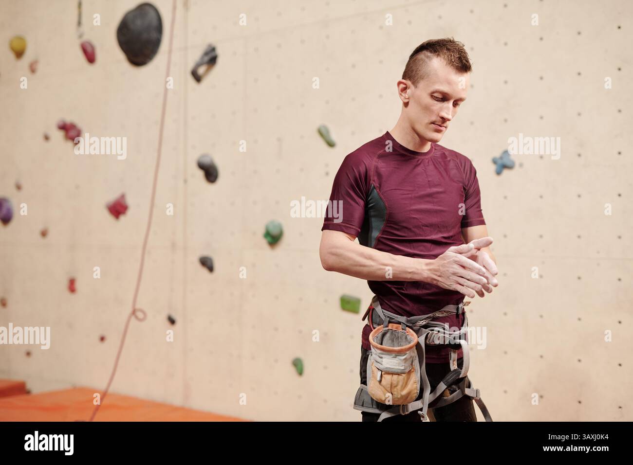 Contemporary sportsman applying talc on his hand palms before wall ...