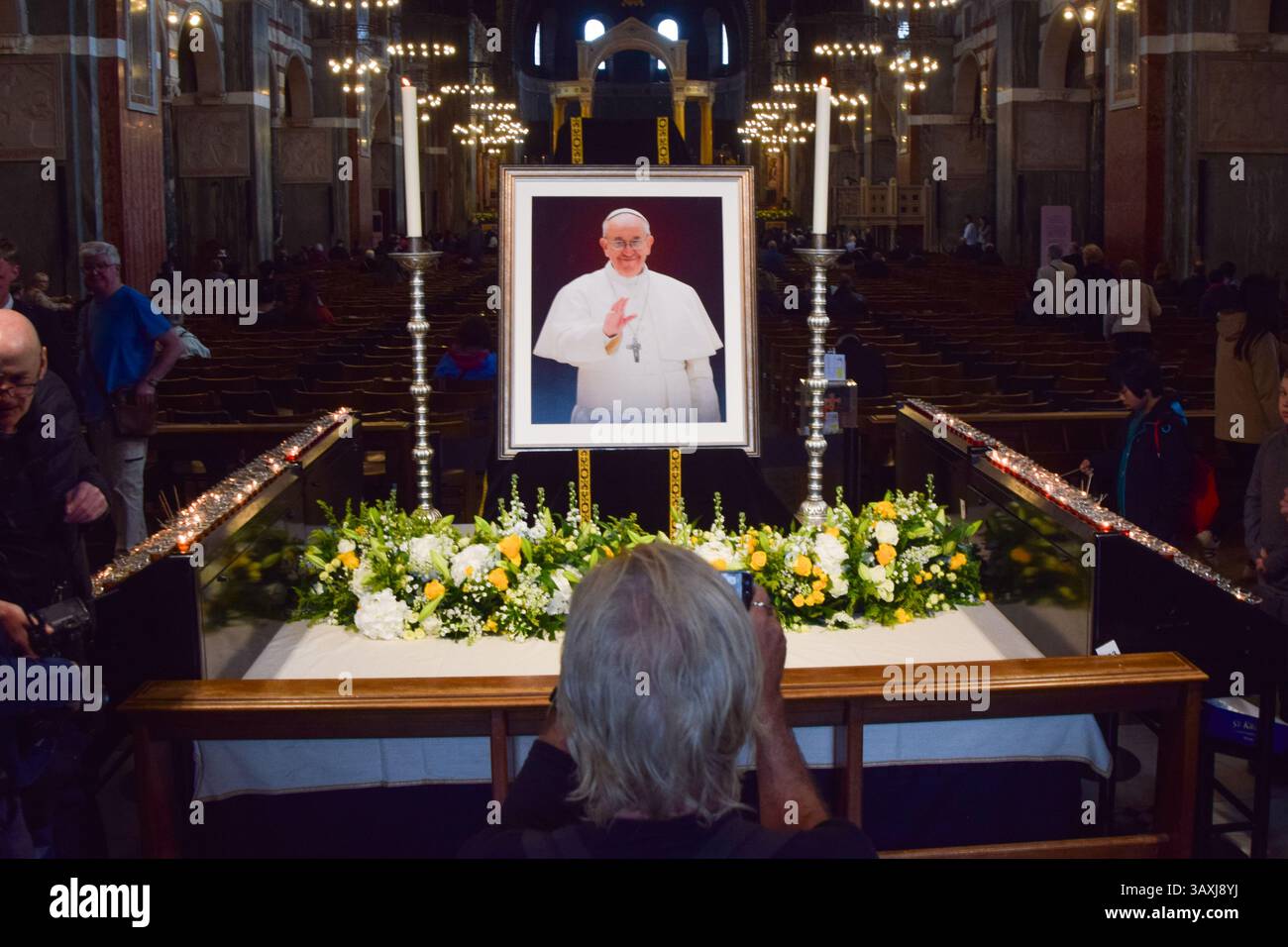 London, UK. 21st April 2025. People light candles next to a picture of ...