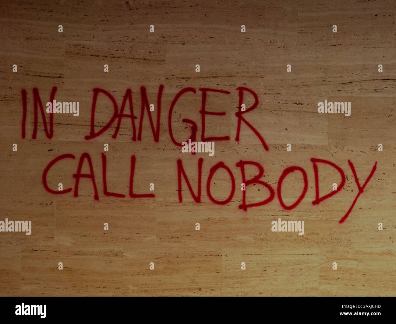 Red Text Graffiti "In Danger call Nobody" on Beige Textured Wall ...