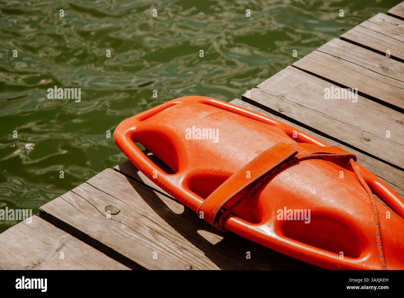 Lifeguard rescue float on wooden dock by calm lake water. Weekend ...