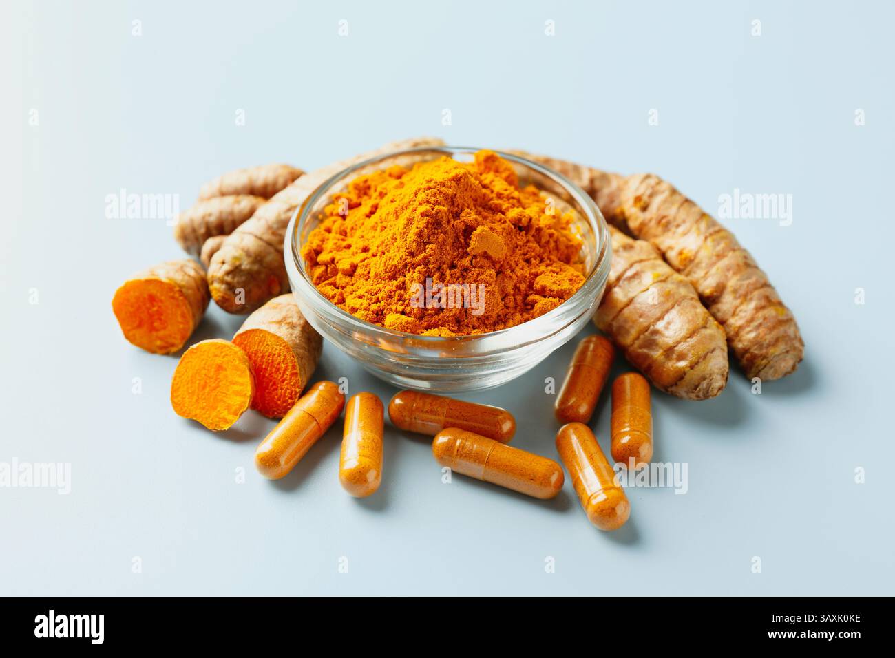 Turmeric capsules, powder and roots on light blue background, closeup ...