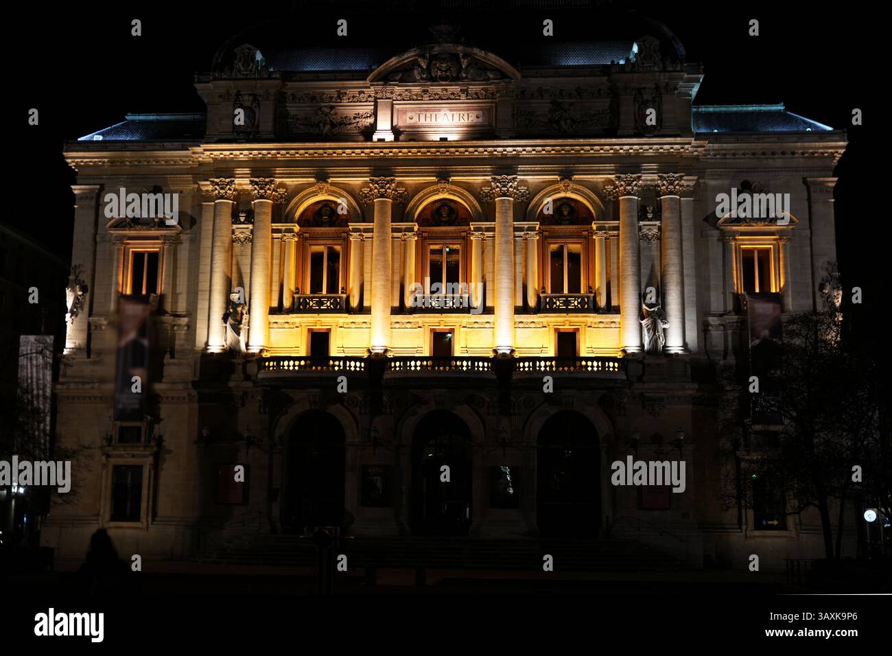 Front view of a grand historic theater at night, with classical columns ...