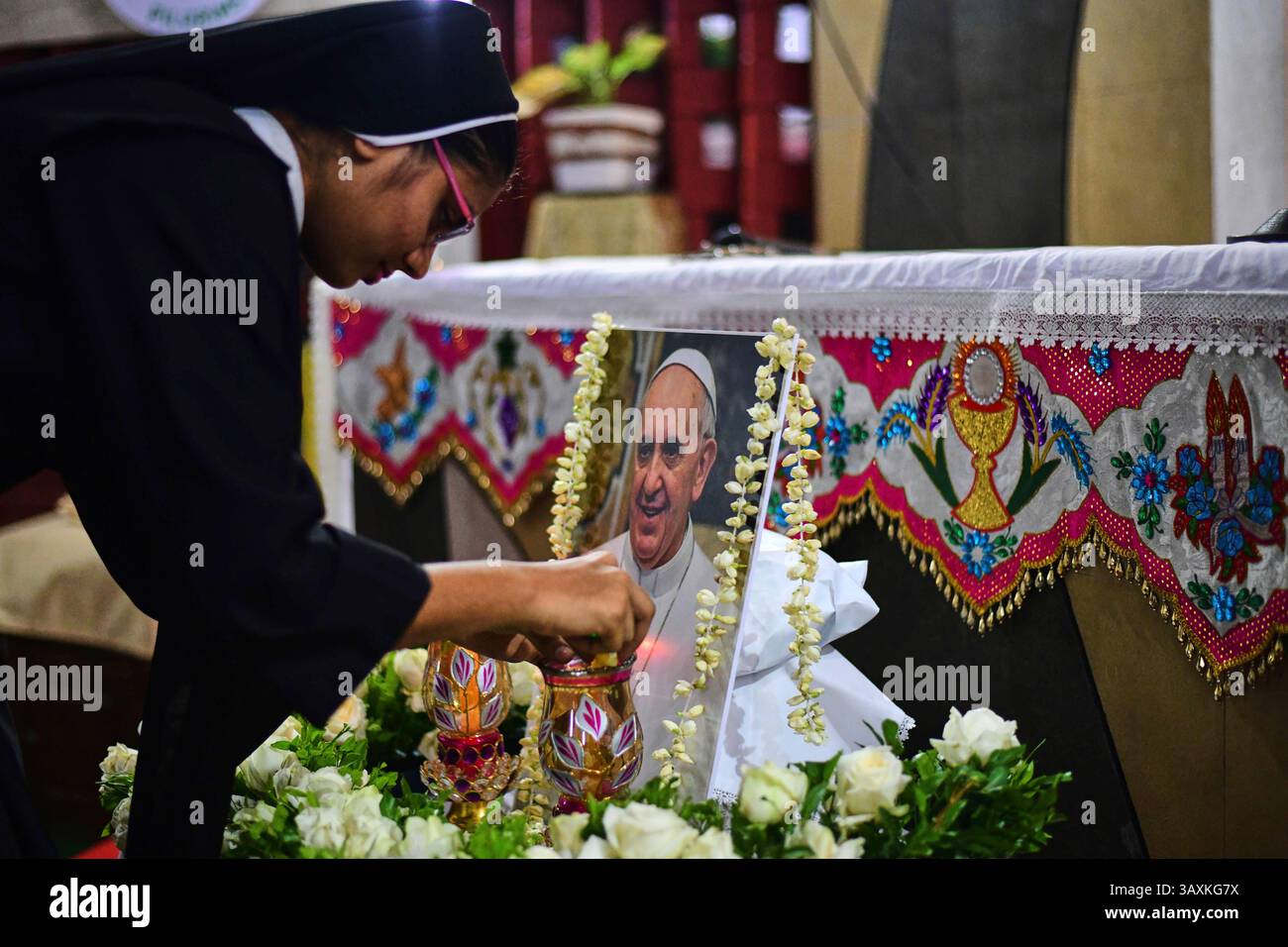 An Indian Catholic nun lights a candle before a portrait of Pope ...