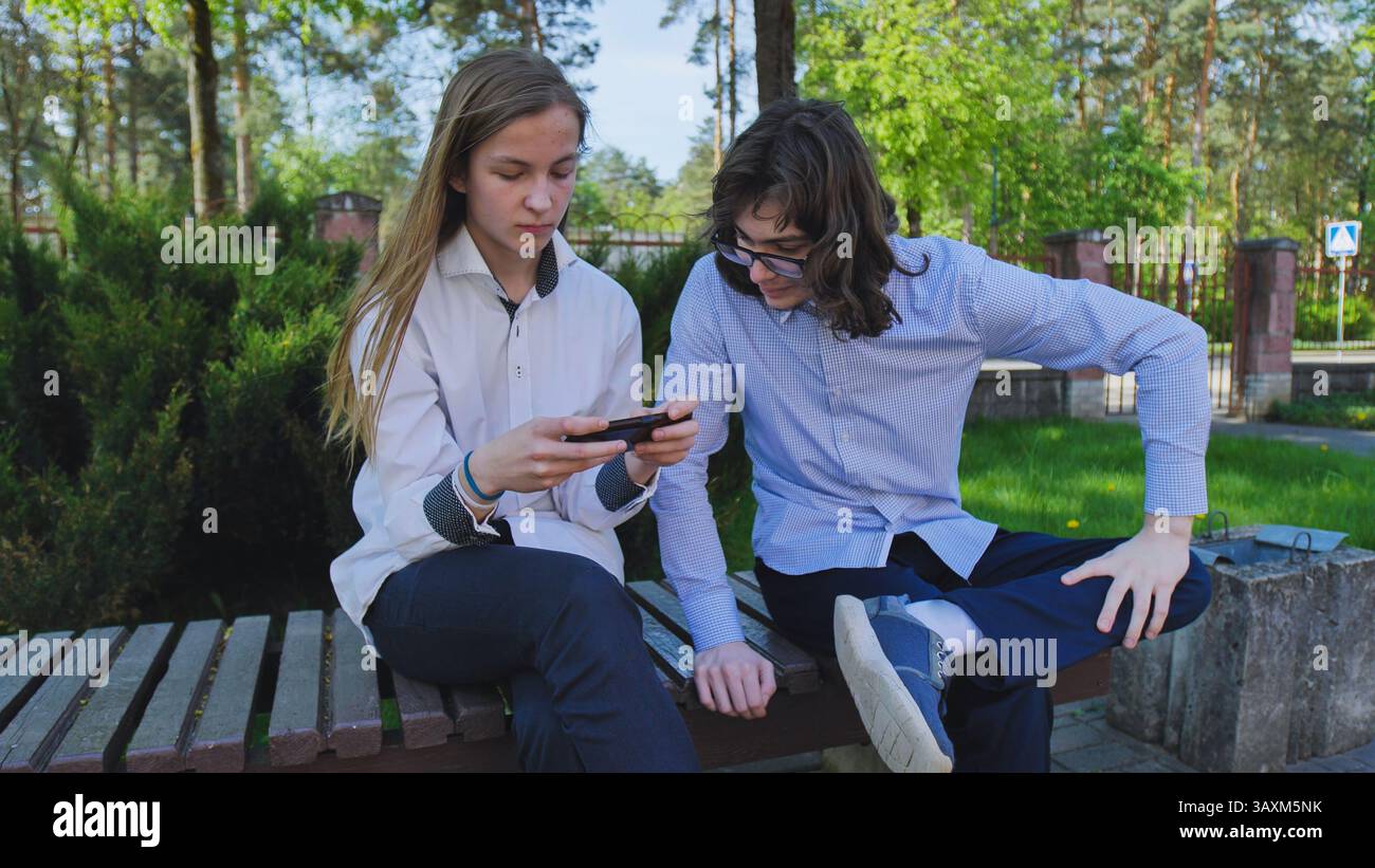 During their school break, two high school students sit on a bench ...
