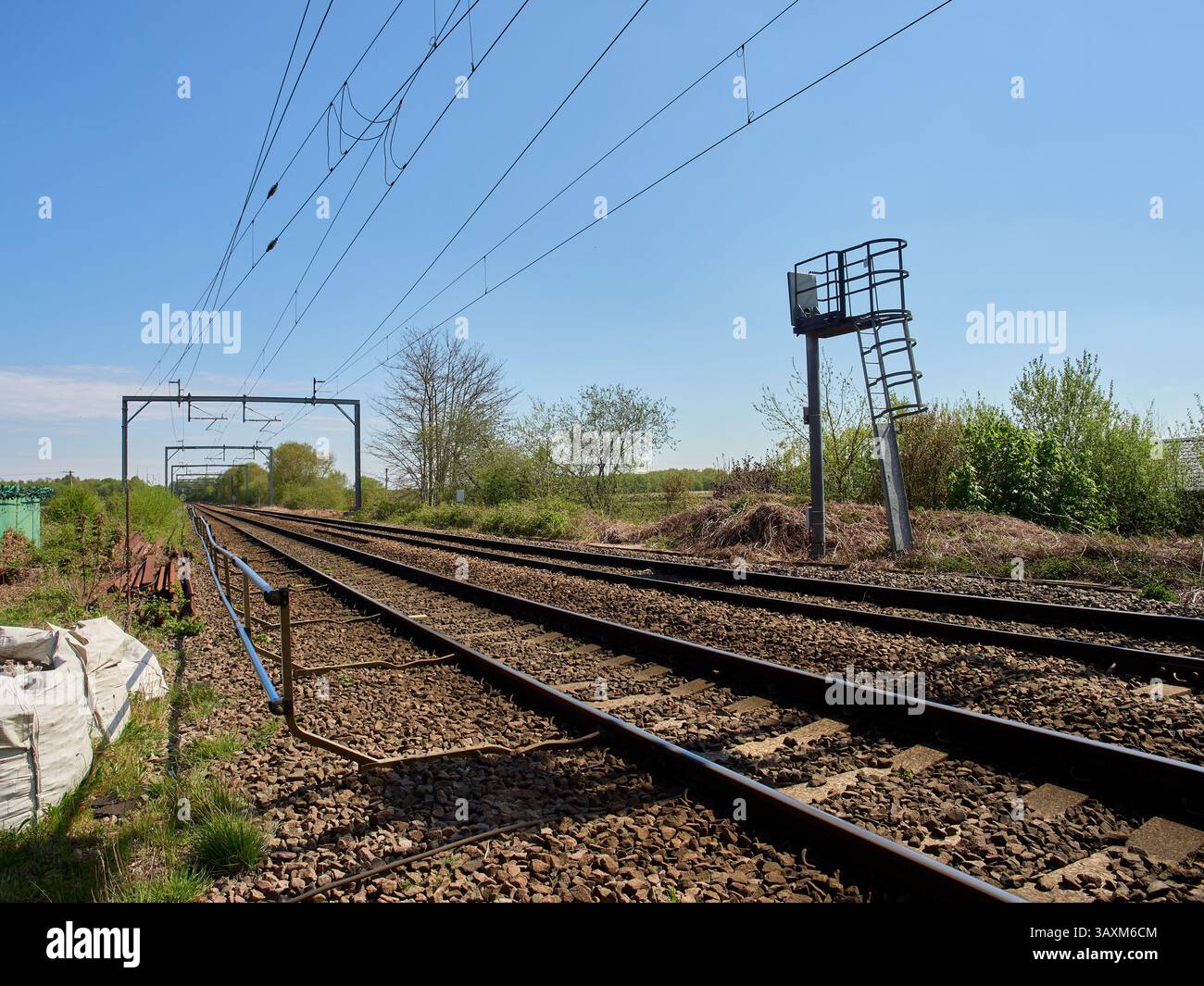Railroad overhead electric power supply lines above train track, blue ...