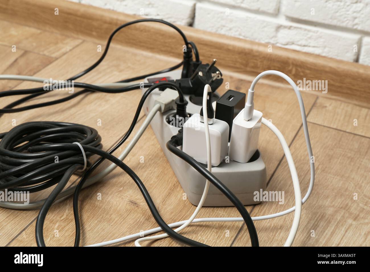 Extension power board overloaded with plugs on wooden floor, closeup ...