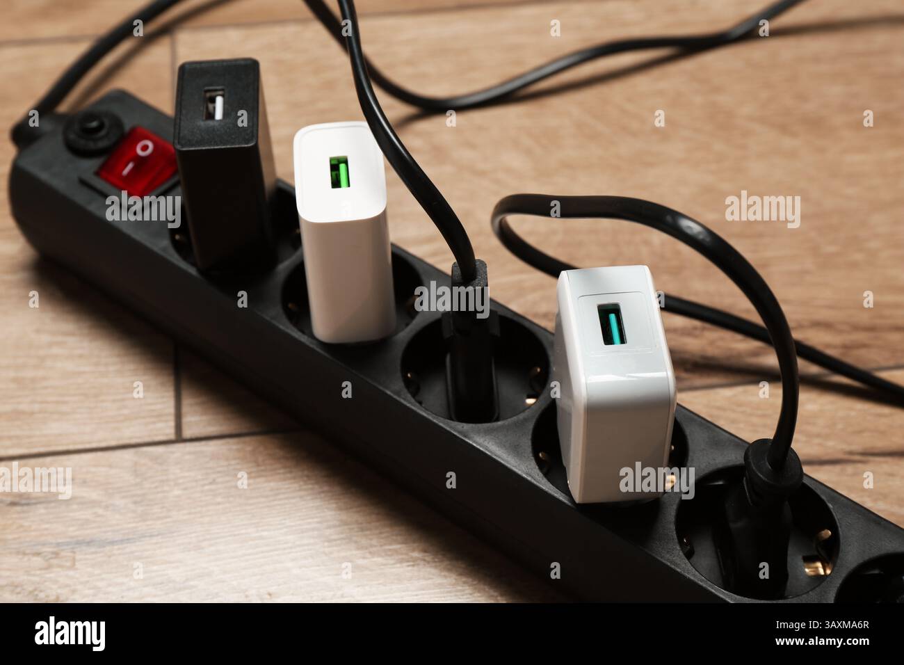 Extension power board overloaded with plugs on wooden floor, closeup ...
