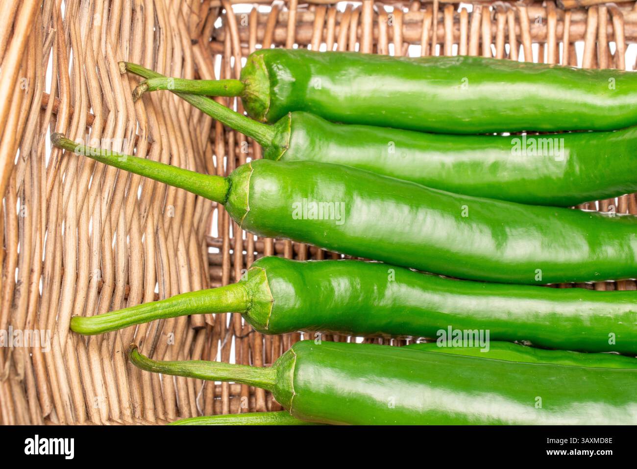 A few pods of ripe organic, spicy green hot pepper with a wicker basket ...