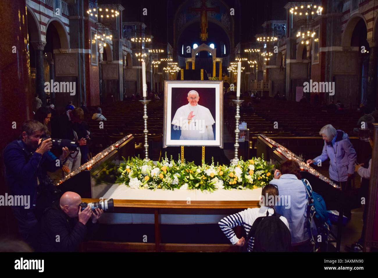 London, UK. 21st Apr, 2025. People light candles next to a picture of ...
