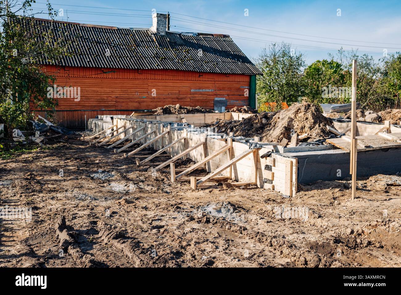 Building strip foundation for new house next to old wooden house Stock ...
