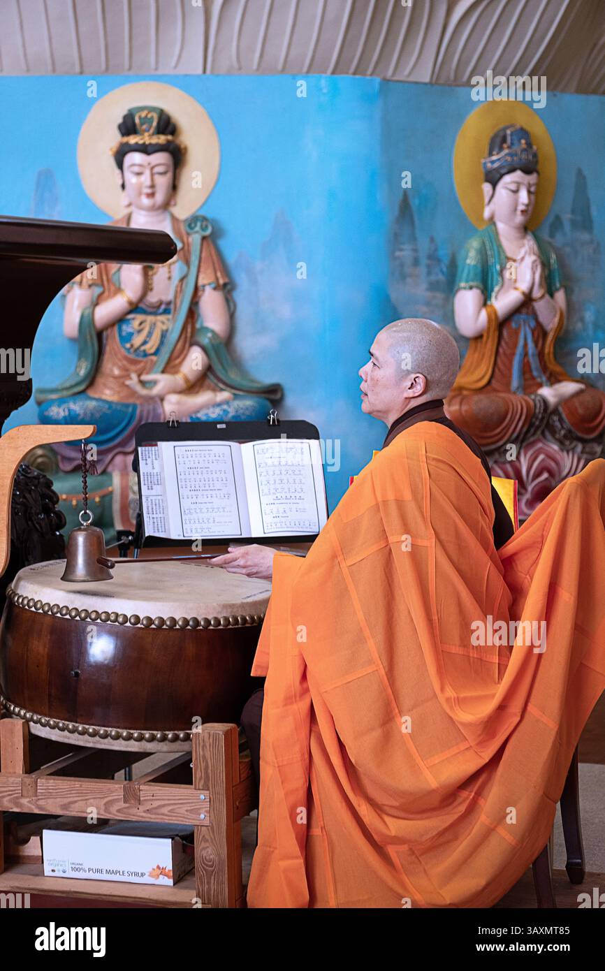 A female monk plays 2 percussion instruments at a Quinming service ...